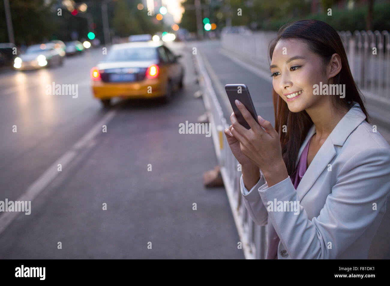 Young woman waiting for taxi with smart phone Stock Photo - Alamy