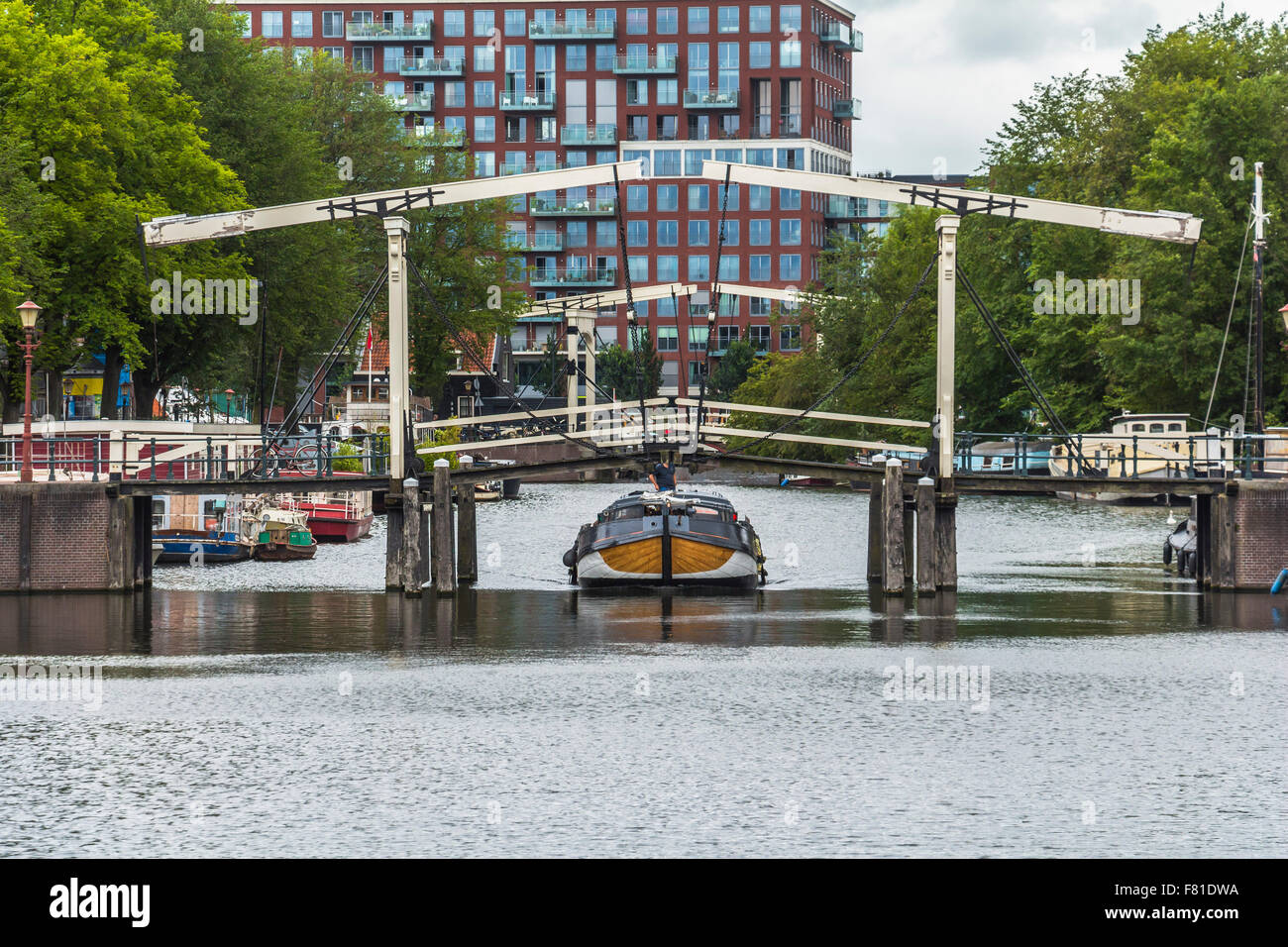 Boat under bridge on canal in Amsterdam Stock Photo - Alamy