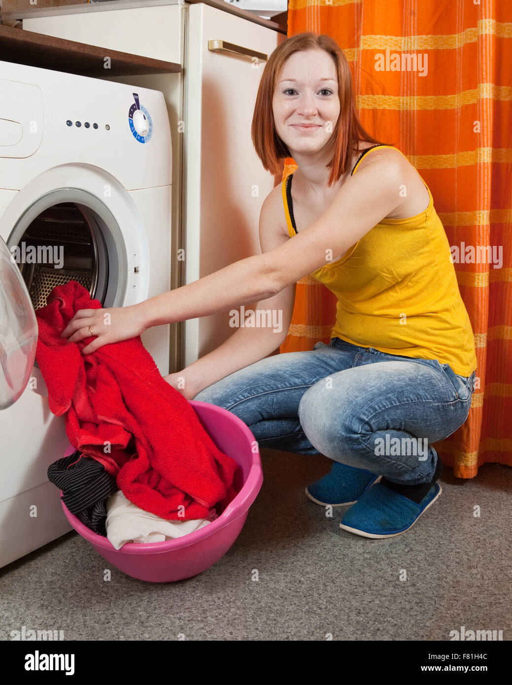 woman putting clothes into washing machine and looking at camera Stock ...