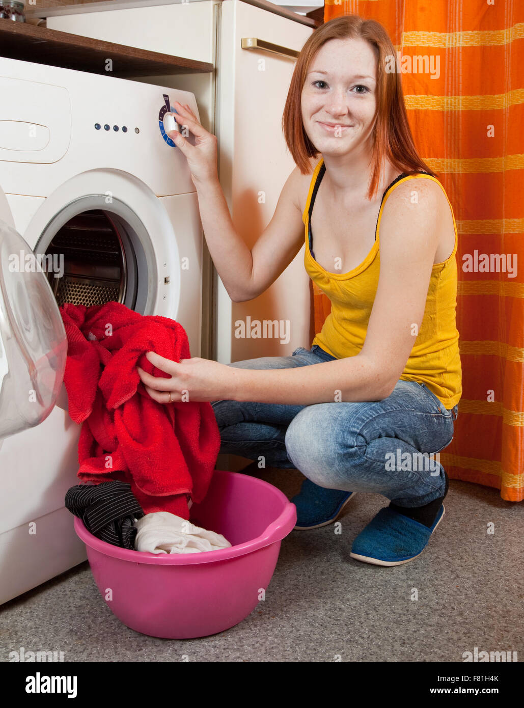 Young woman loading the washing machine in kitchen Stock Photo - Alamy