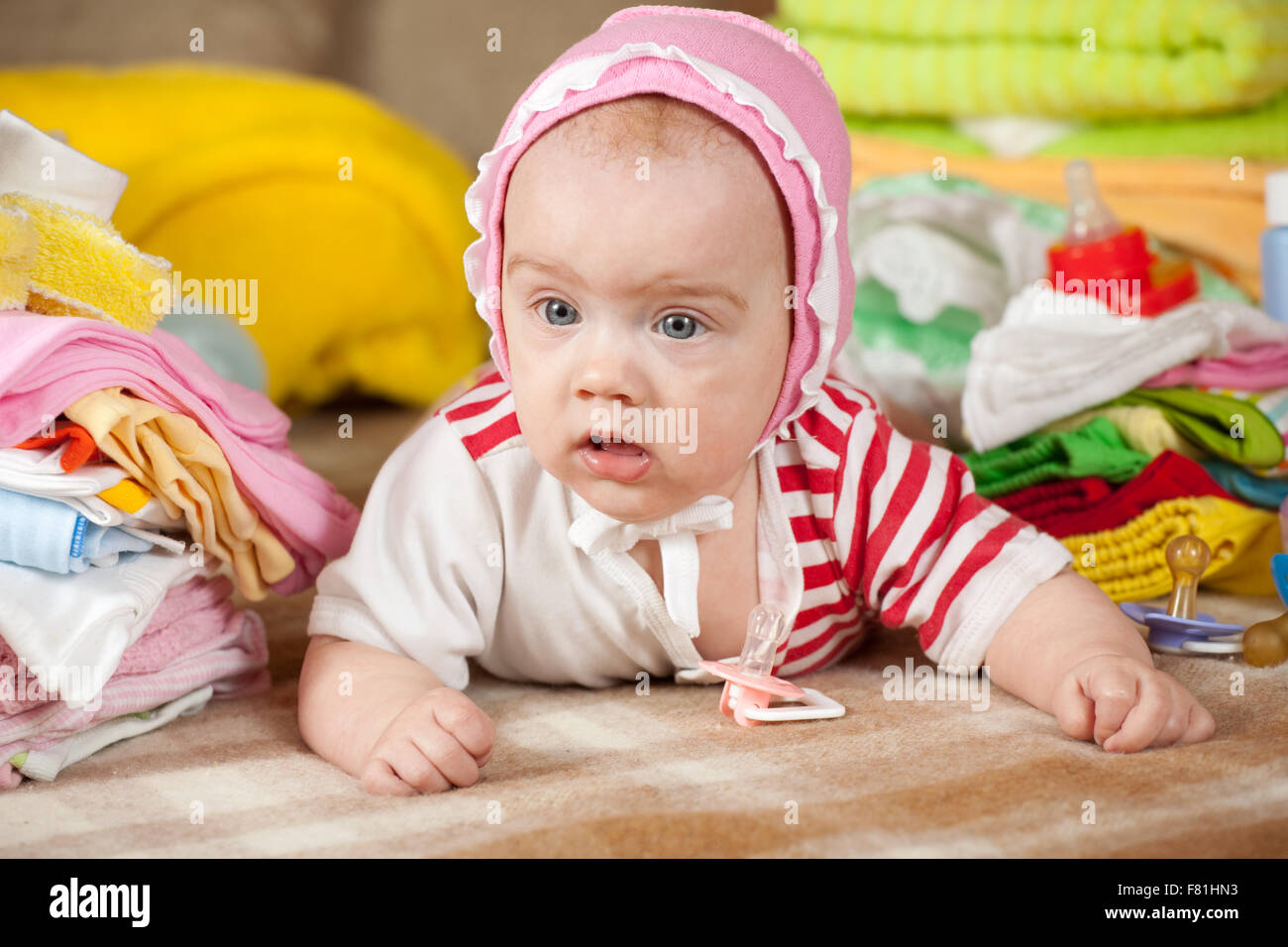 baby girl with stacked of children's clothes Stock Photo - Alamy