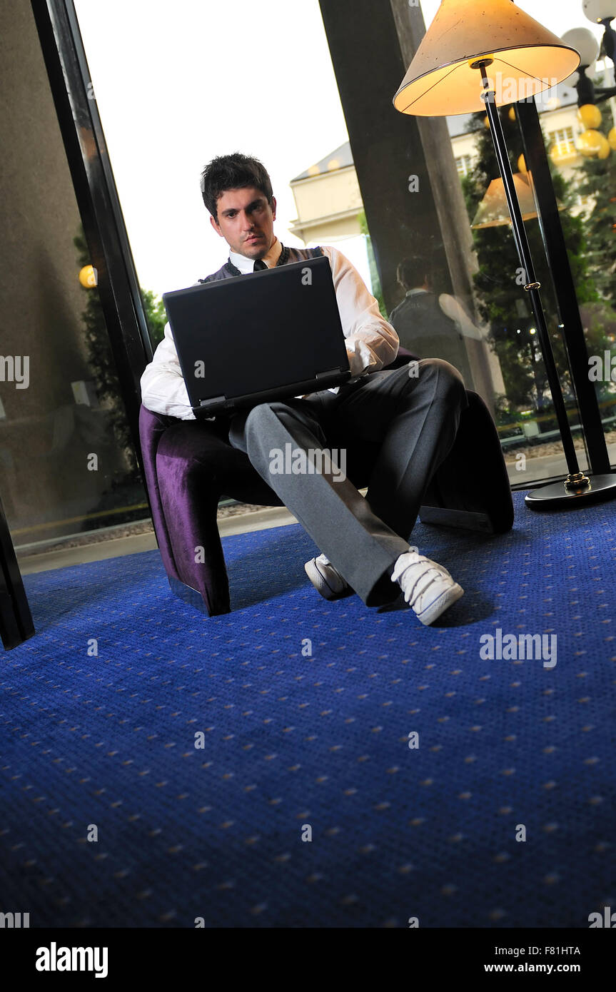 Happy young man sitting relaxed working on computer Stock Photo - Alamy