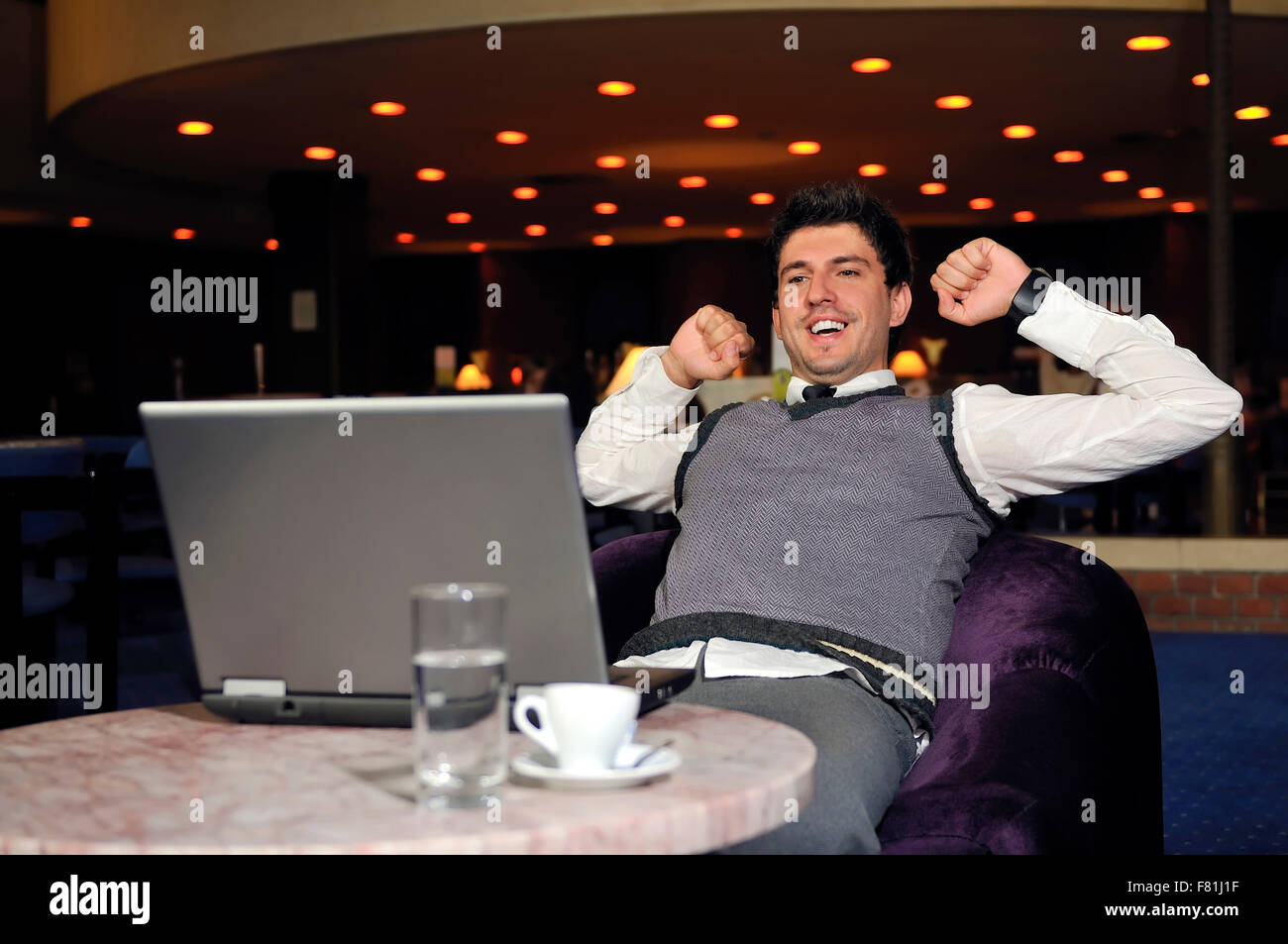 Happy young man sitting relaxed working on computer Stock Photo - Alamy
