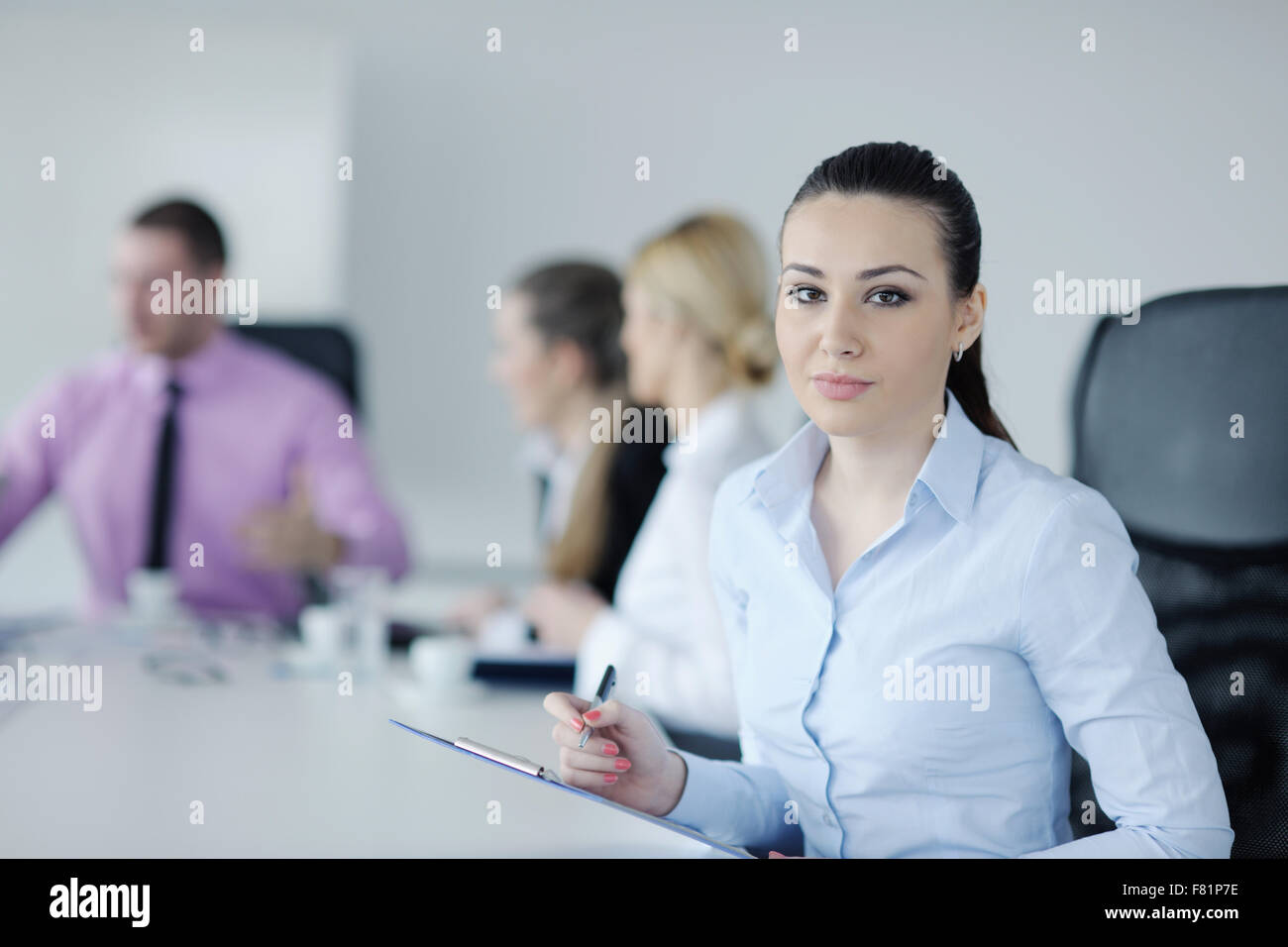 Successful business woman standing with her staff in background at ...