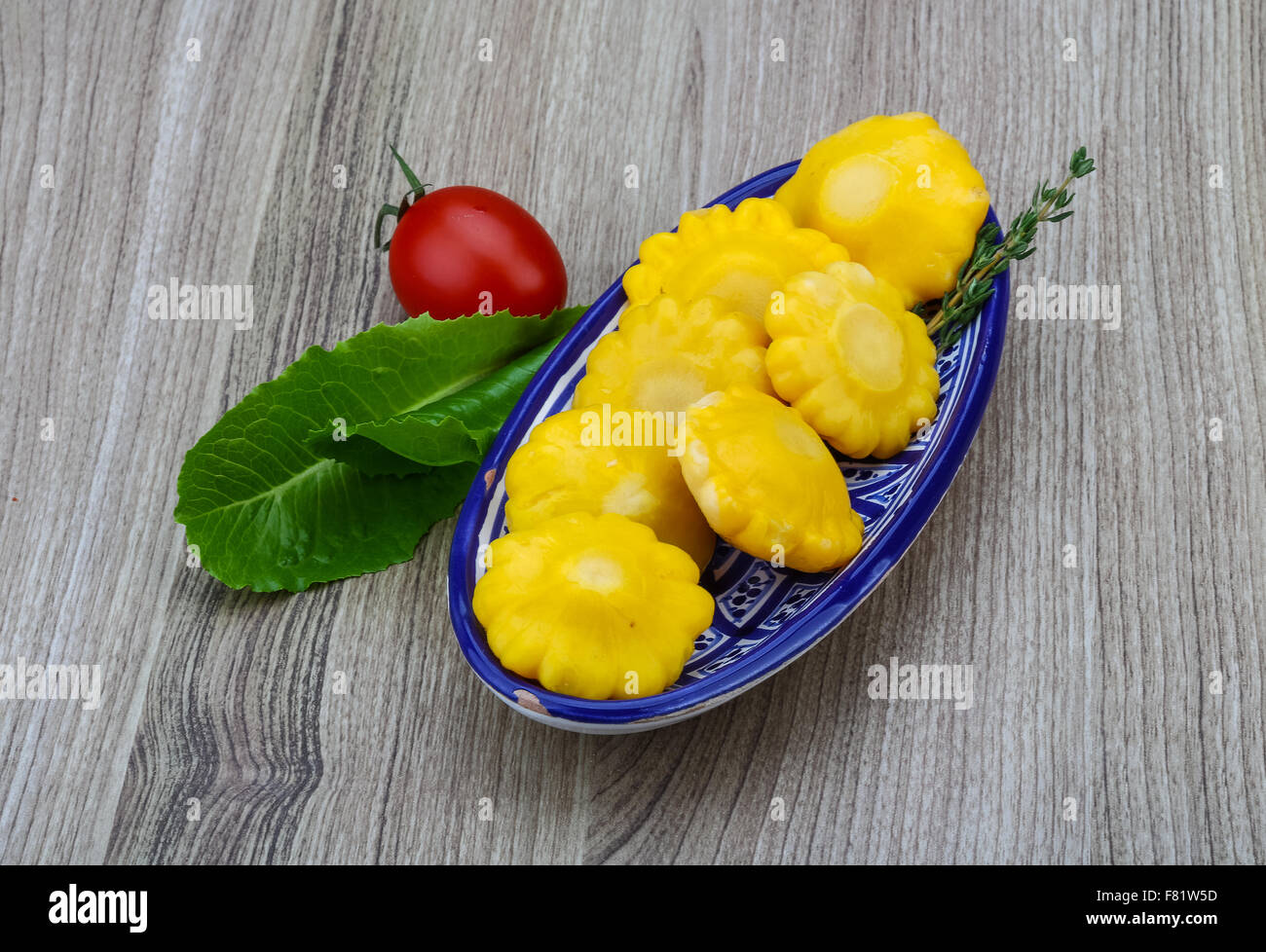 Yellow Pickled patissons with thyme leaves on the wood background Stock ...