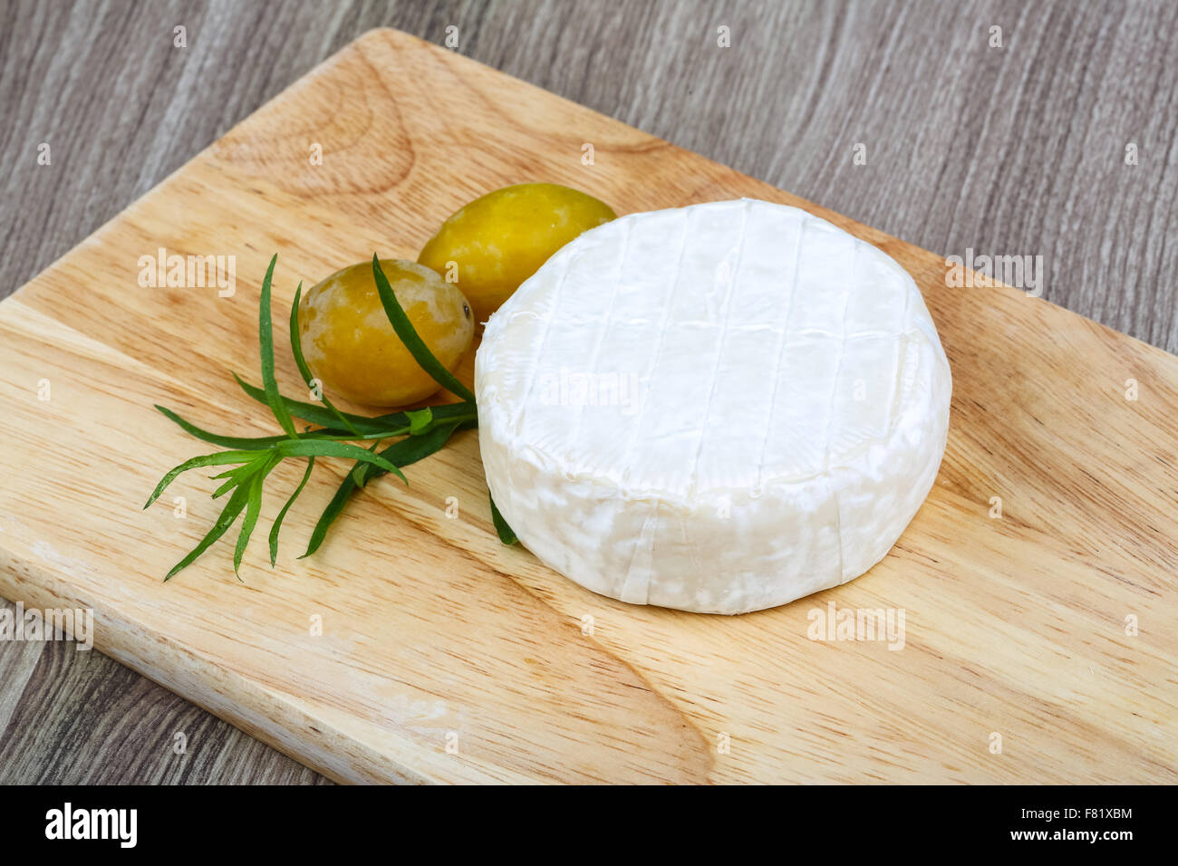 Brie cheese with yellow plums and estragon leaves Stock Photo - Alamy