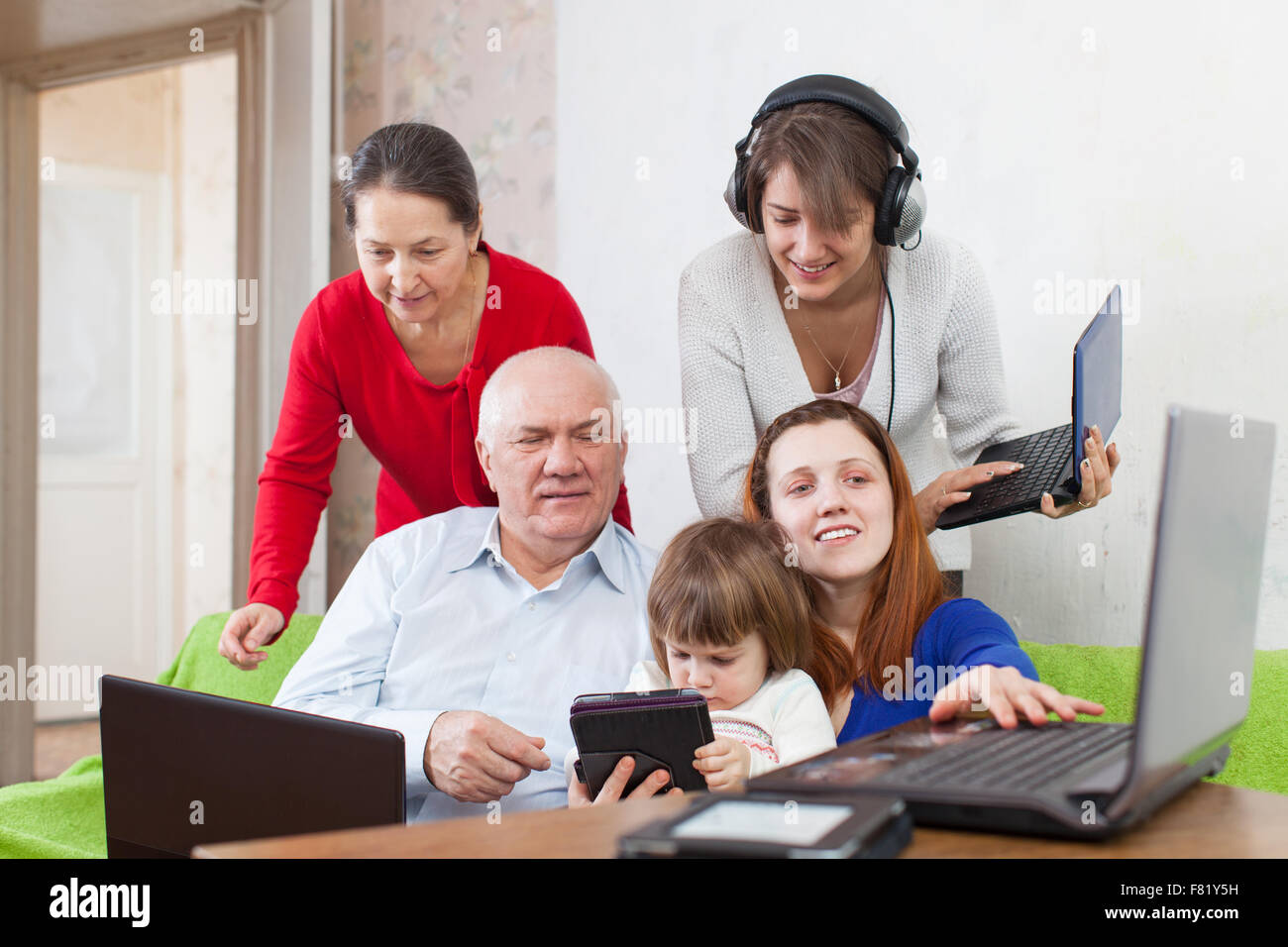 people uses few various electronic devices in home interior Stock Photo ...