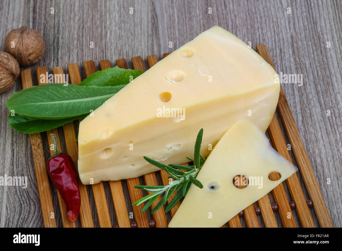 Triangle yellow cheese with rosemary, pepper and salad leaves Stock ...