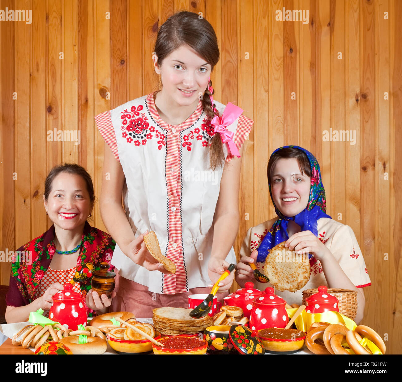 Women in traditional clothes eating pancake during Shrovetide Stock ...