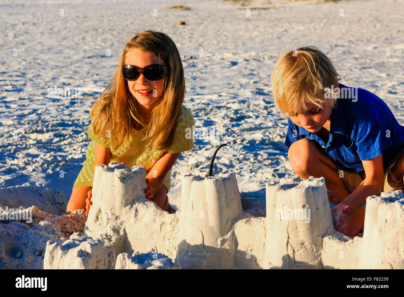 Young Brother And Sister Posing At Sunset By The Sand Castle They Built