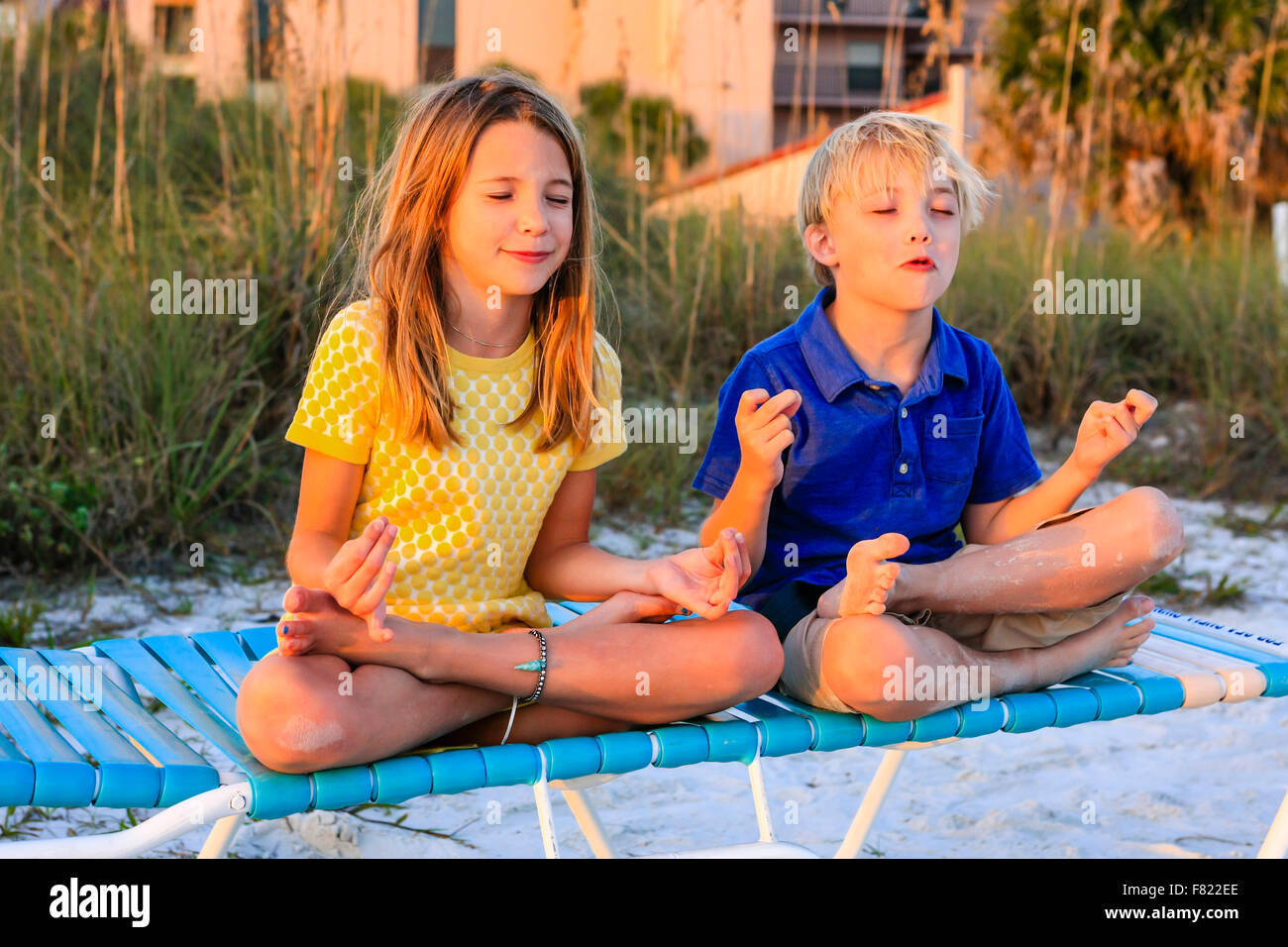 Pre-teen girl with her younger brother try yoga on the beach at Siesta ...