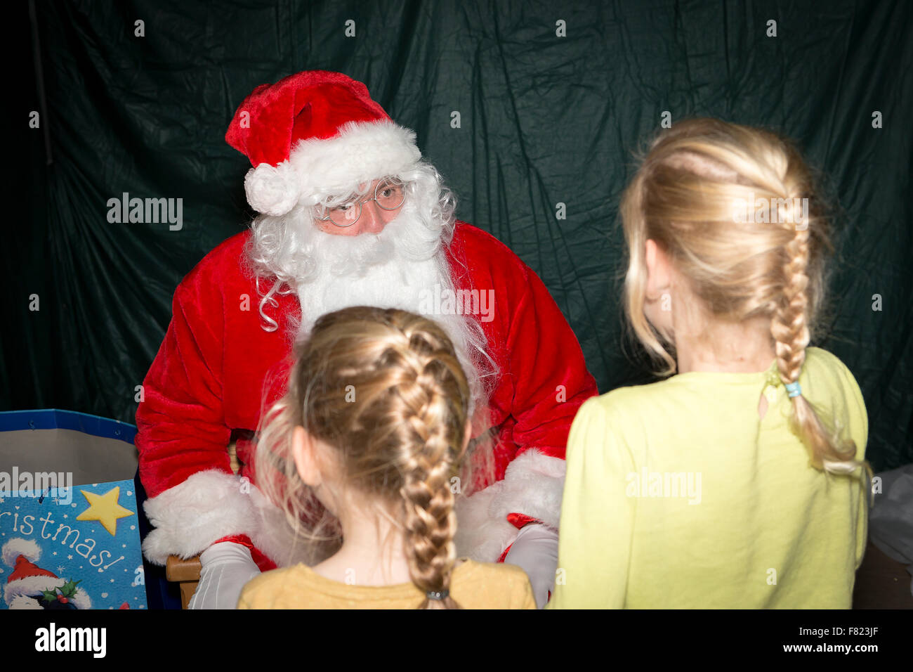 Two young girls talk to Father Christmas in Santa's Grotto Stock Photo ...