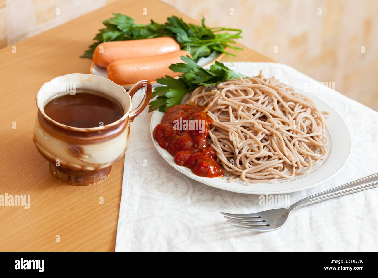 Supper. Spaghetti pasta with ketchup and sausages on table Stock Photo ...