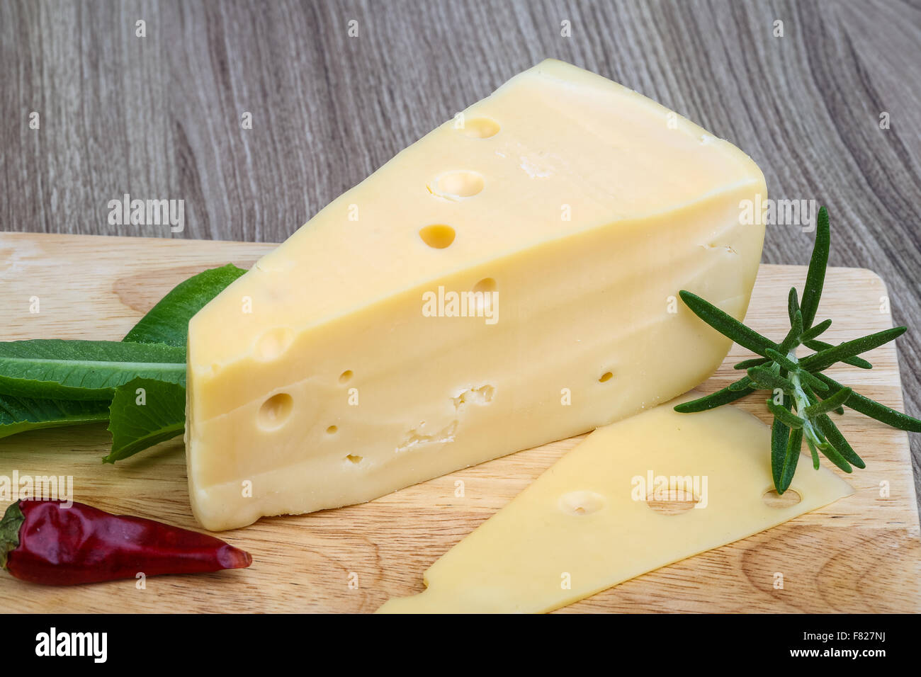 Triangle yellow cheese with rosemary, pepper and salad leaves Stock ...