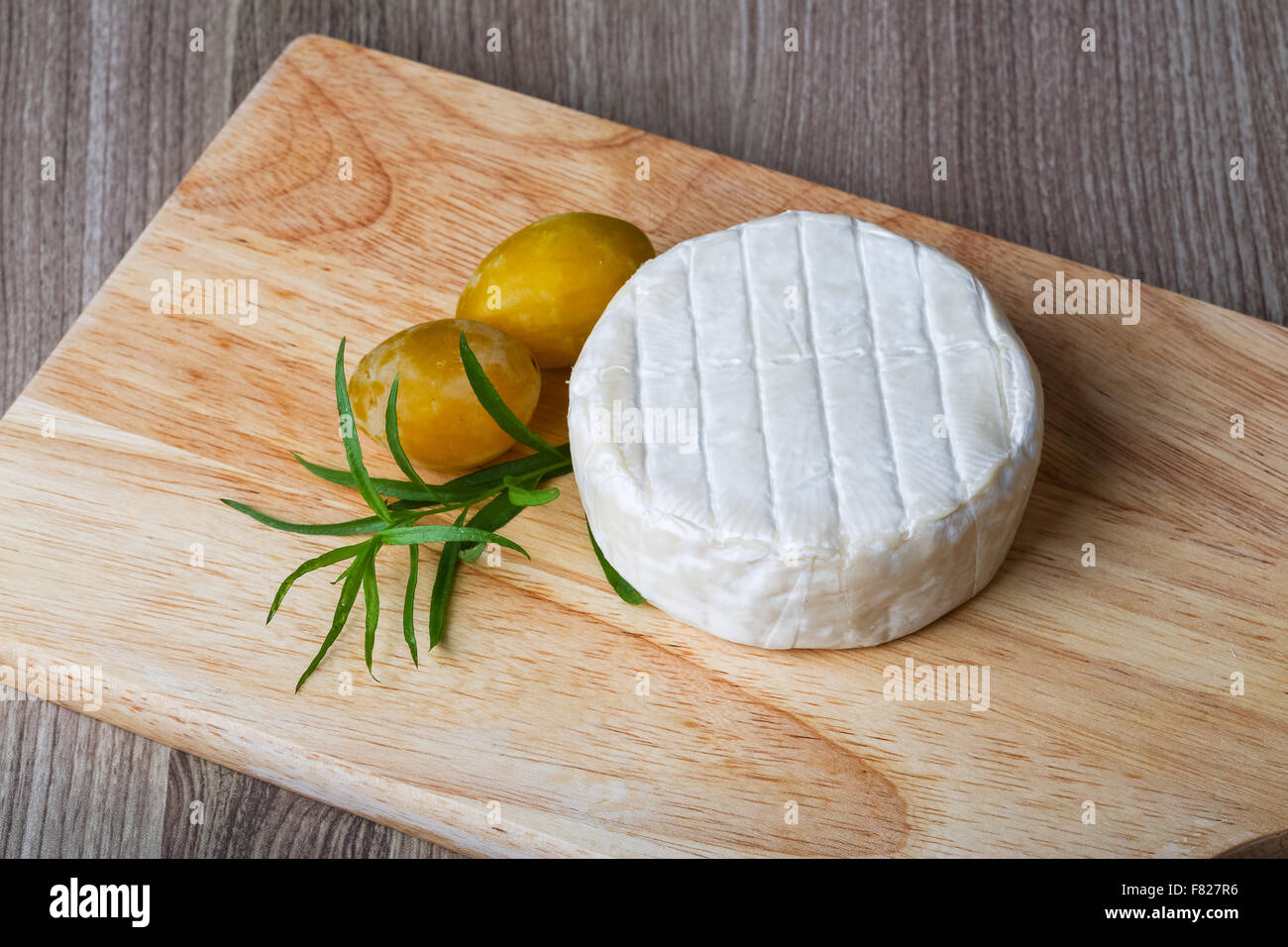 Brie cheese with yellow plums and estragon leaves Stock Photo - Alamy