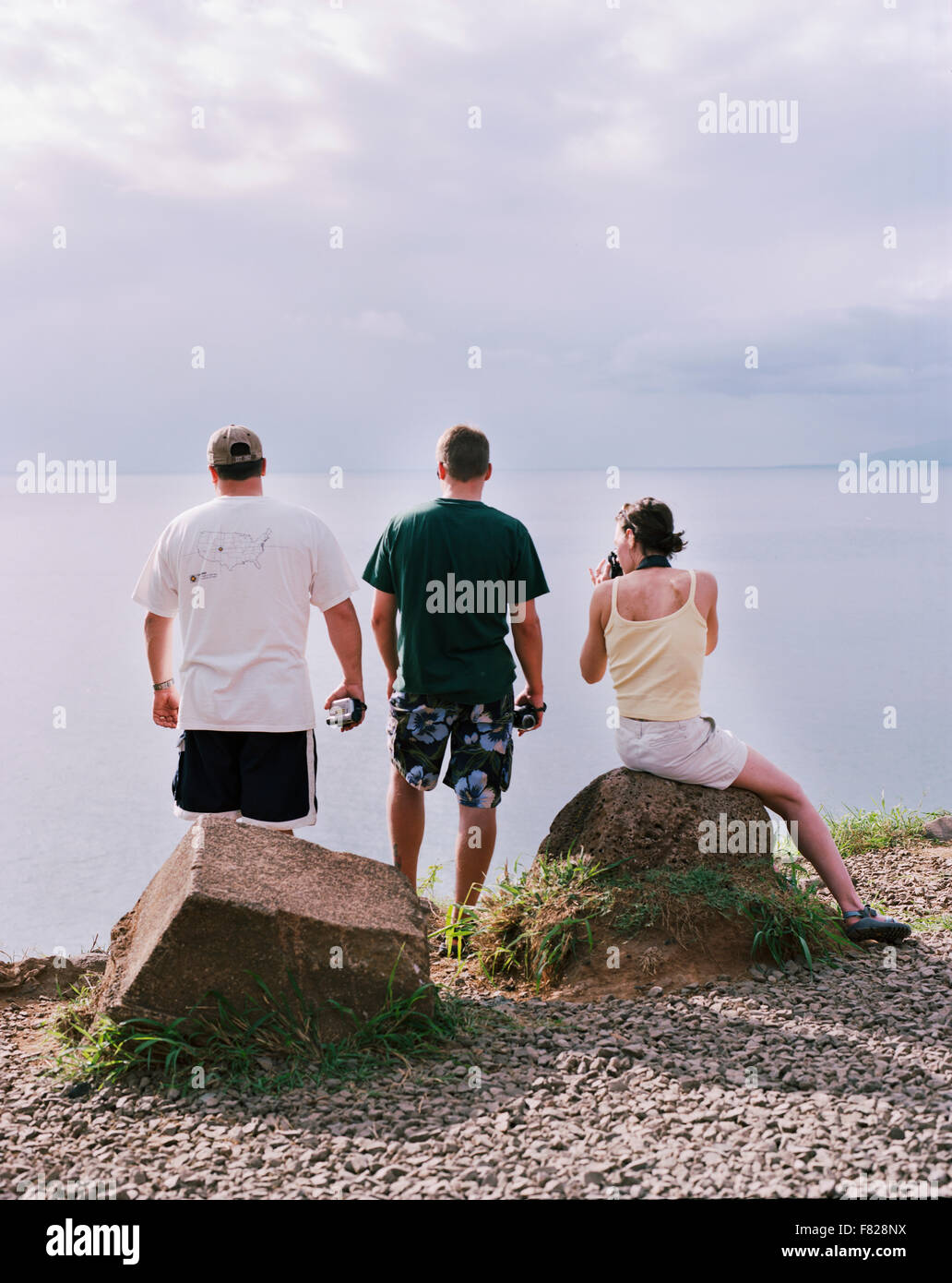 Three tourists overlooking ocean Stock Photo - Alamy