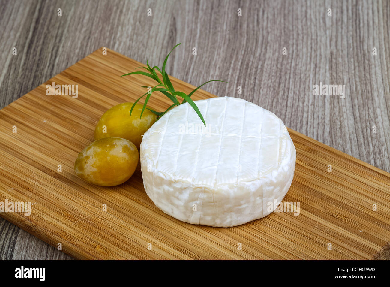 Round Brie cheese with yellow plums and estragon Stock Photo - Alamy