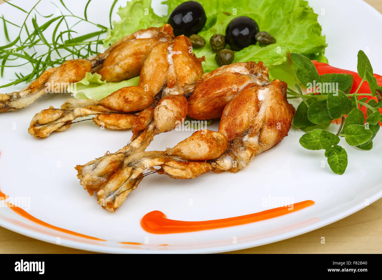 Fried frog legs with herbs on the wood background Stock Photo - Alamy