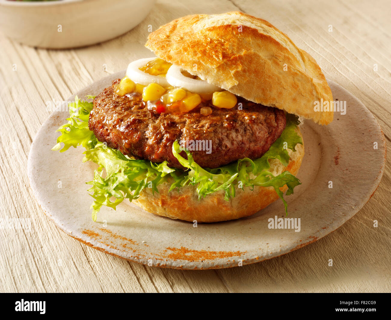 Close of a beef burger, hambuger in a white crusty roll with sweetcorn ...