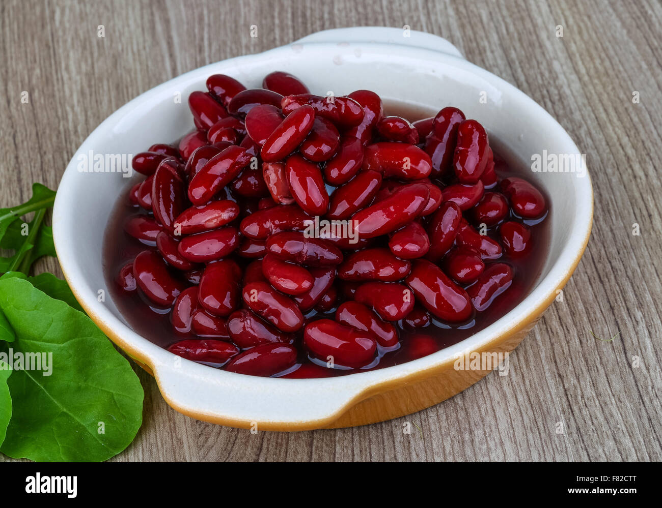 Red kidney on the bowl with ruccola leaves wood background Stock Photo ...