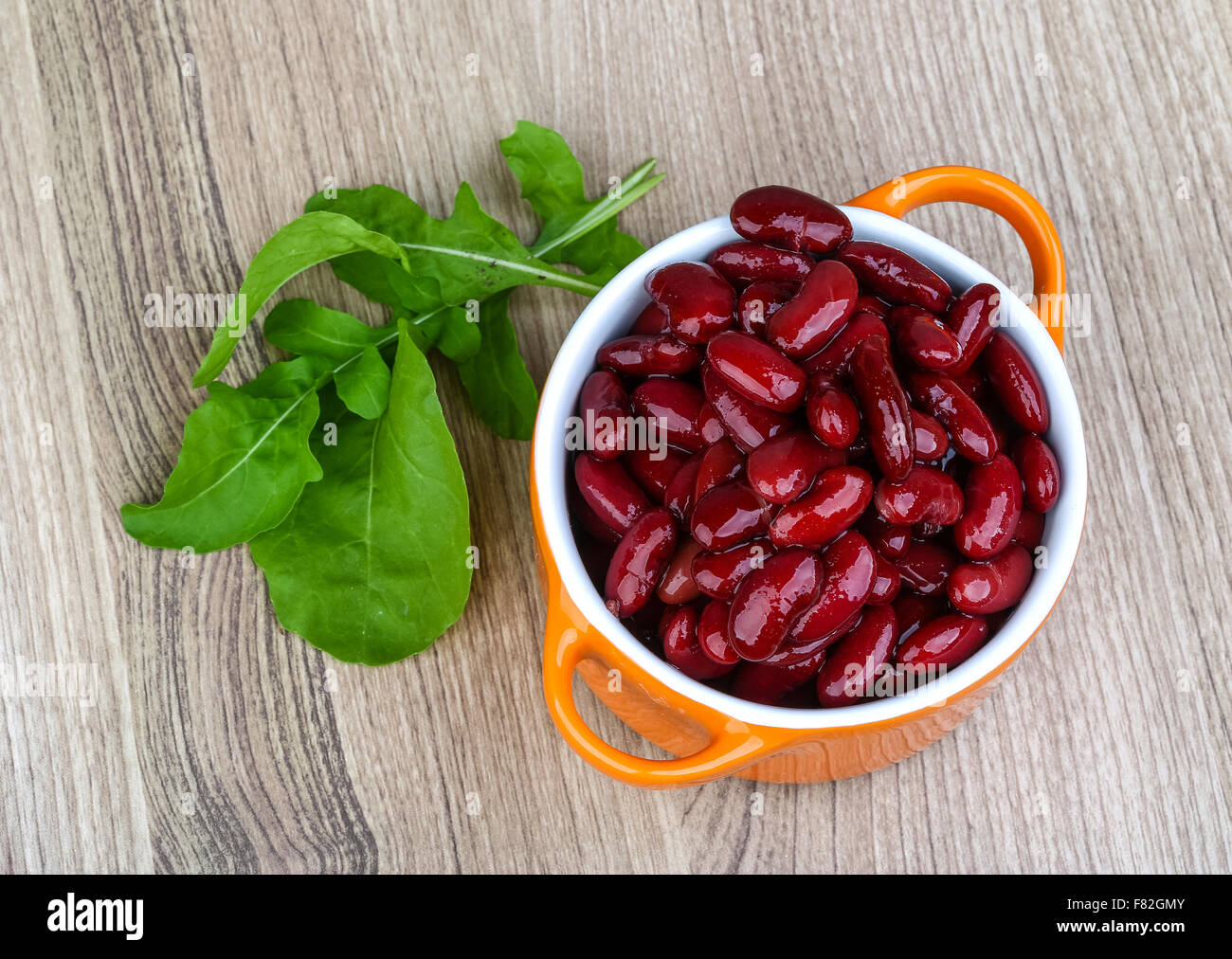 Red kidney on the bowl with ruccola leaves wood background Stock Photo ...