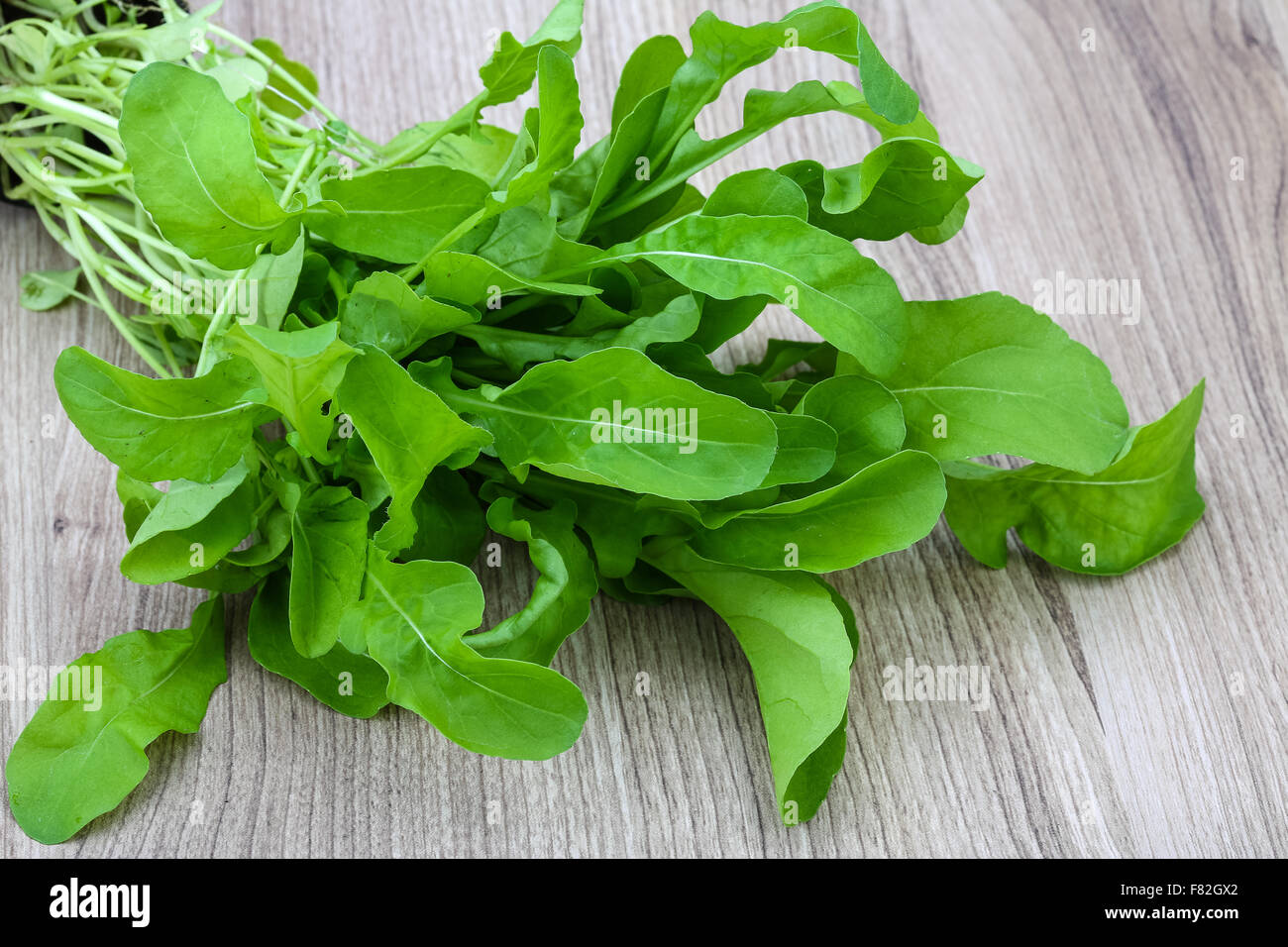 Fresh green Ruccola leaves heap on the wood background Stock Photo - Alamy