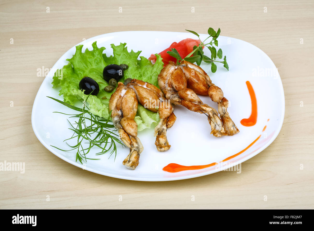 Fried frog legs with herbs on the wood background Stock Photo - Alamy