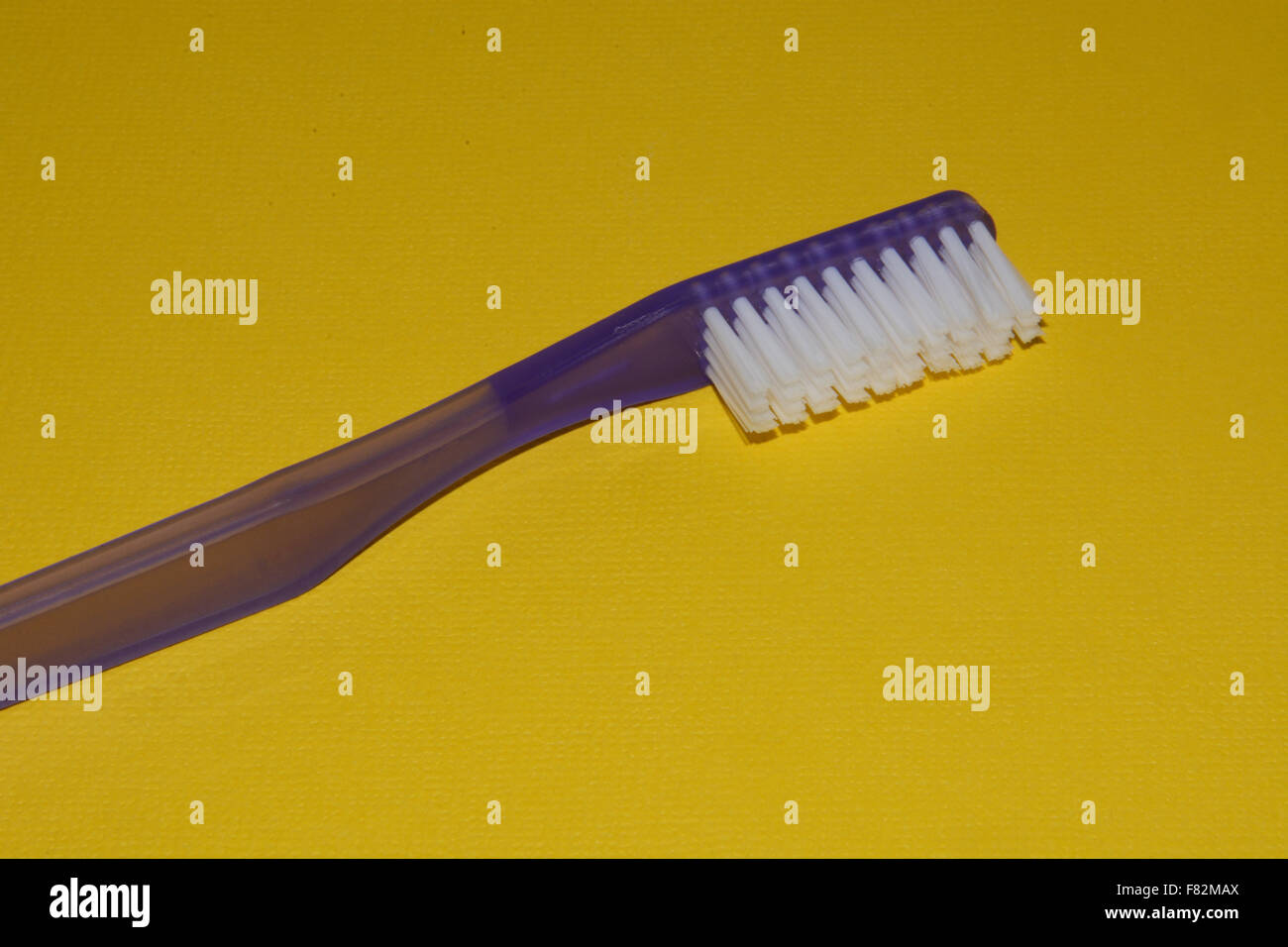 Purple toothbrush on yellow background Stock Photo - Alamy