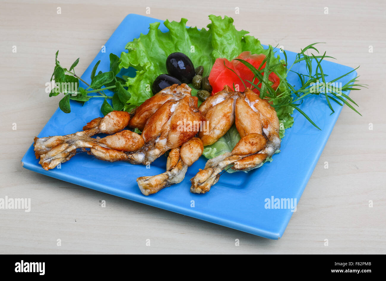 Fried frog legs with olive, herbs and spices Stock Photo - Alamy