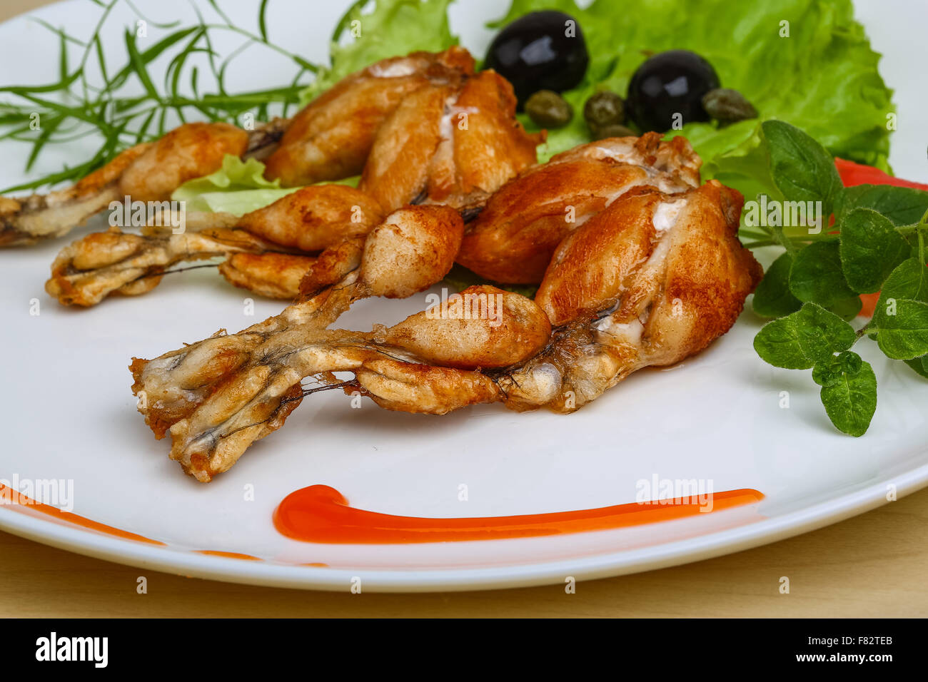 Fried frog legs with herbs on the wood background Stock Photo - Alamy