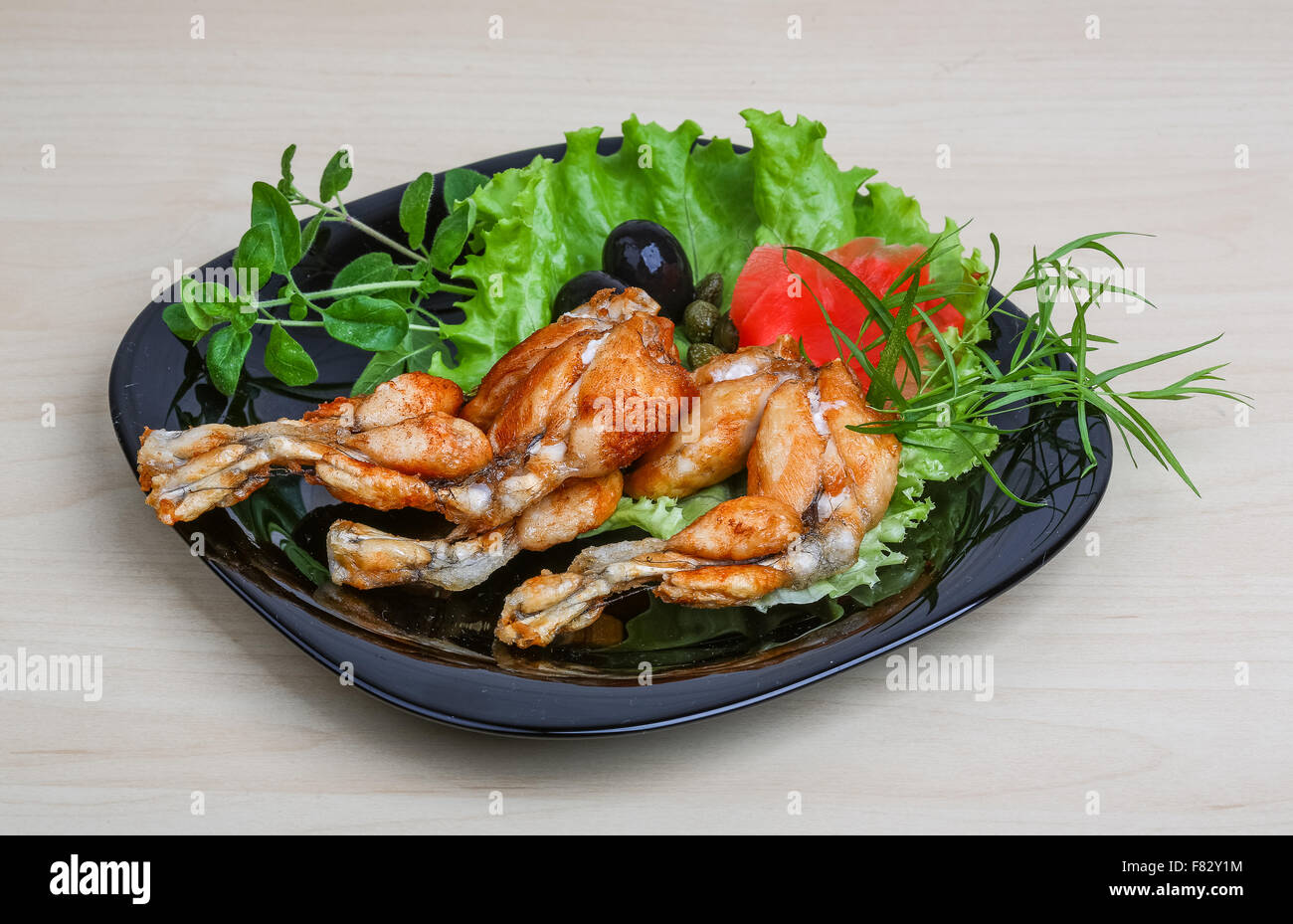 Fried frog legs with olive, herbs and spices Stock Photo - Alamy