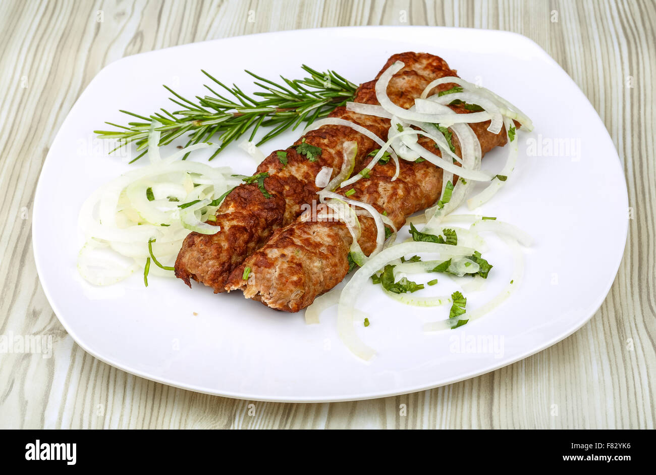 Kebab barbecue with rosemary and onion rings on the wood background ...