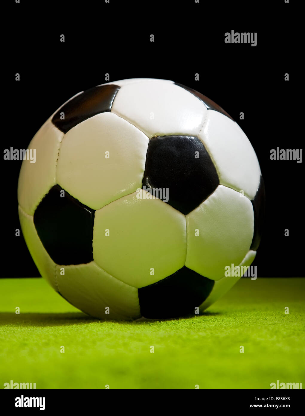 classic football ball on green over black Stock Photo - Alamy
