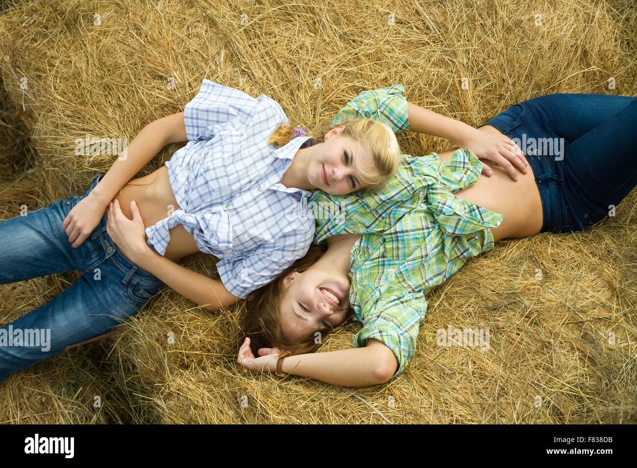 country girls restings on fresh hay bale Stock Photo - Alamy