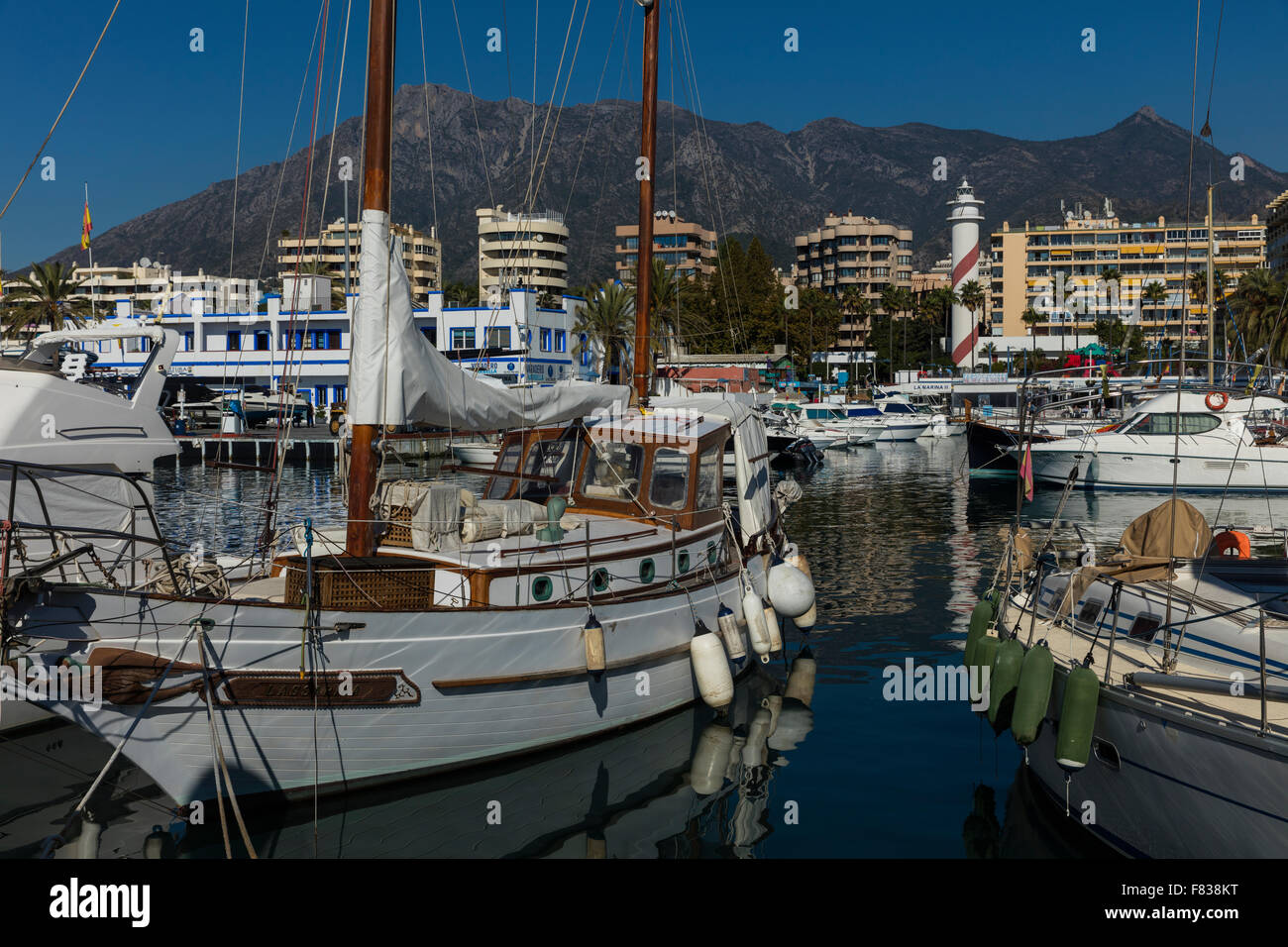 Boats in the marina in Marbella with the lighthouse and mountains in ...