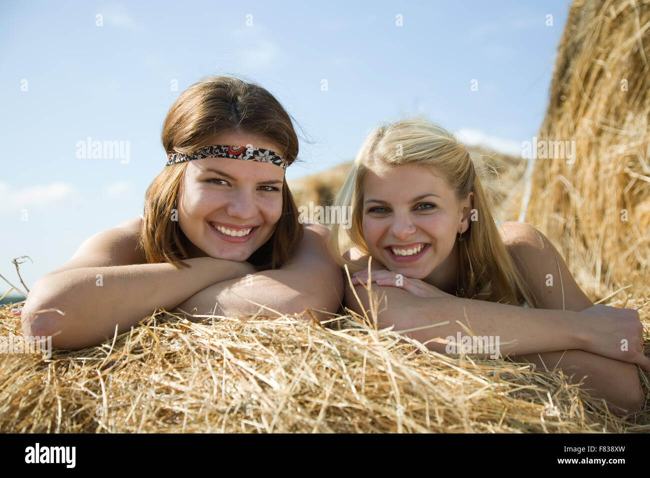 Happy girls on fresh hay at field Stock Photo - Alamy