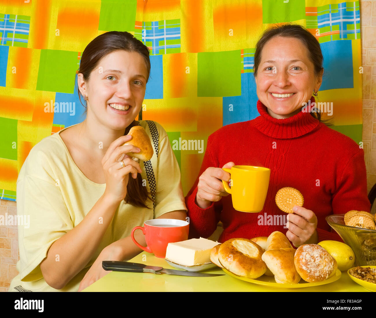 Two smiling women having tea in kitchen Stock Photo - Alamy