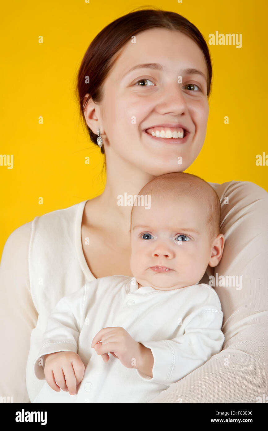 Happy mother with 2 month baby over yellow background Stock Photo - Alamy