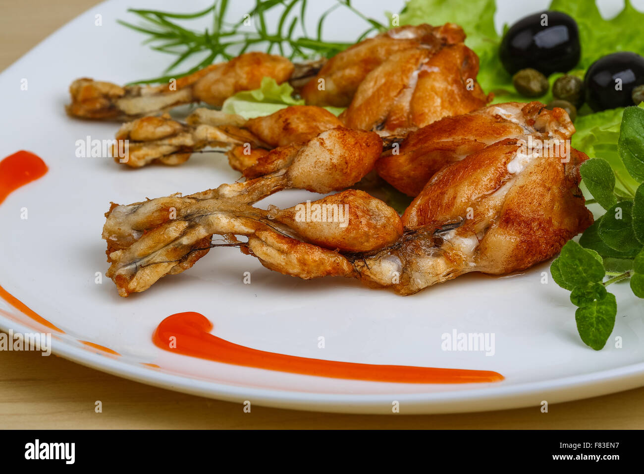 Fried frog legs with herbs on the wood background Stock Photo - Alamy
