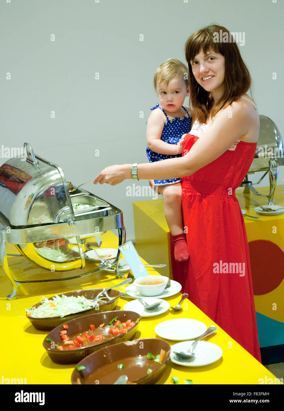 Woman with child gathers food at the buffet Stock Photo - Alamy