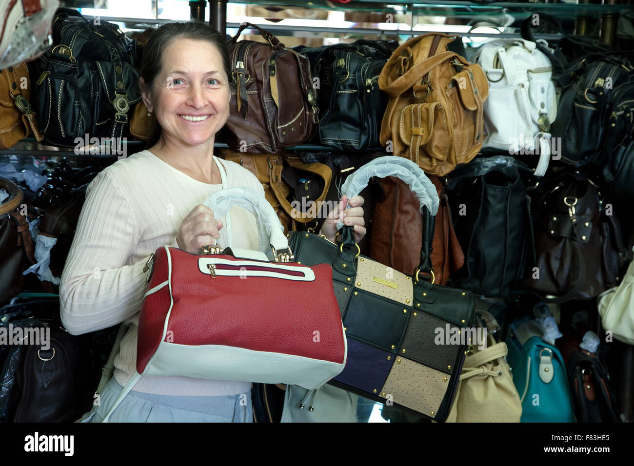 Mature woman chooses leather bag at shop Stock Photo - Alamy