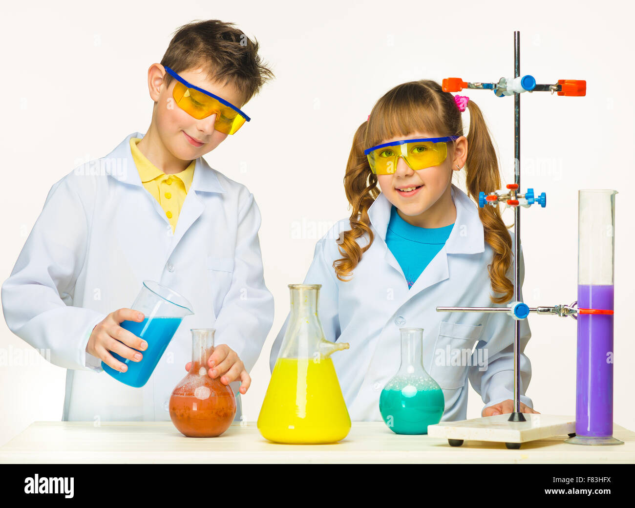 Two cute children at chemistry lesson making experiments on white ...