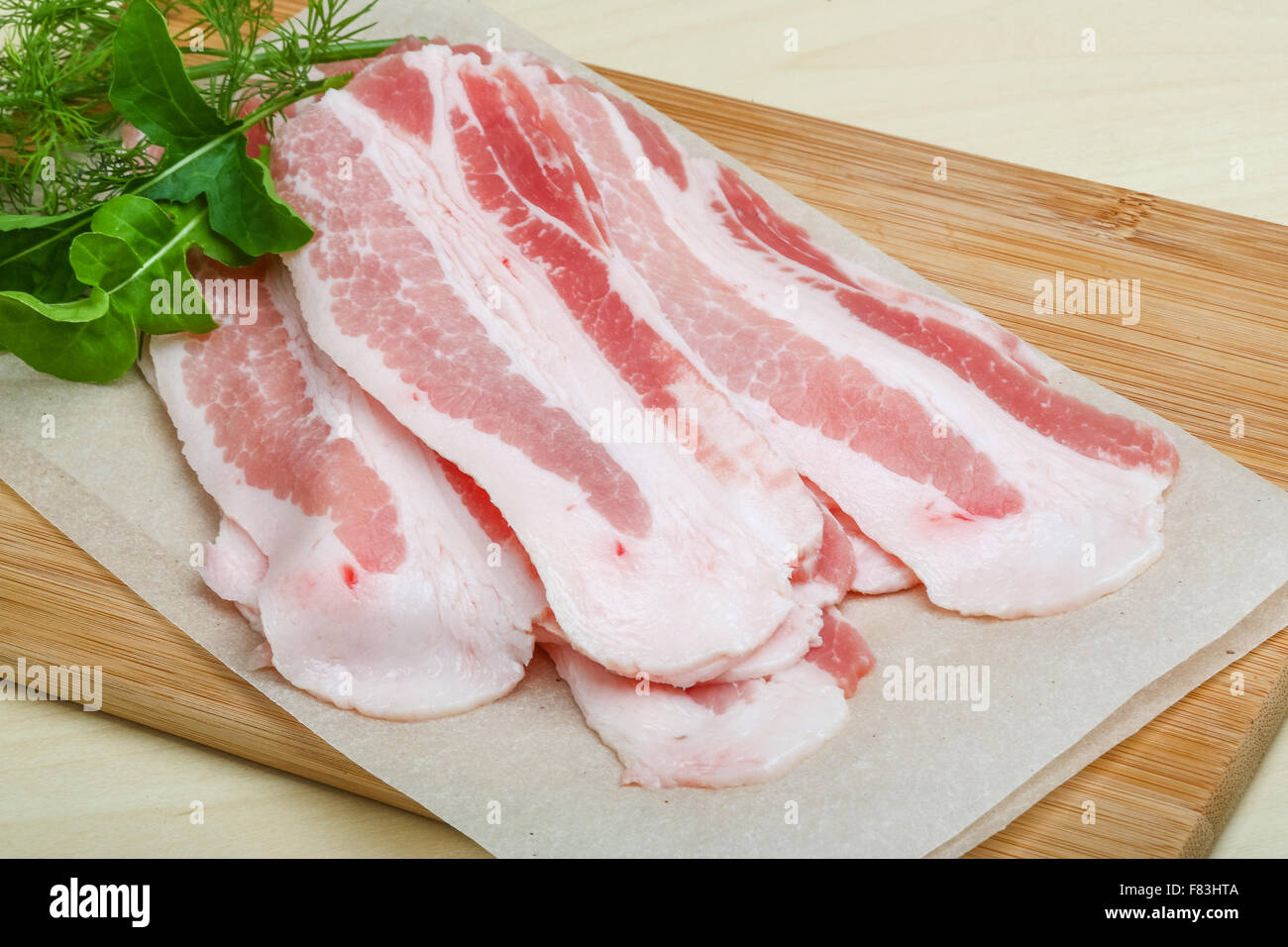 Raw bacon with green herb on the wood background Stock Photo - Alamy
