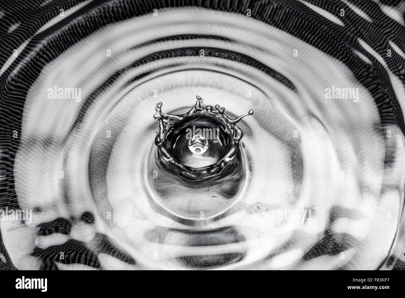 Droplet drops on surface of water creating water splash Stock Photo - Alamy