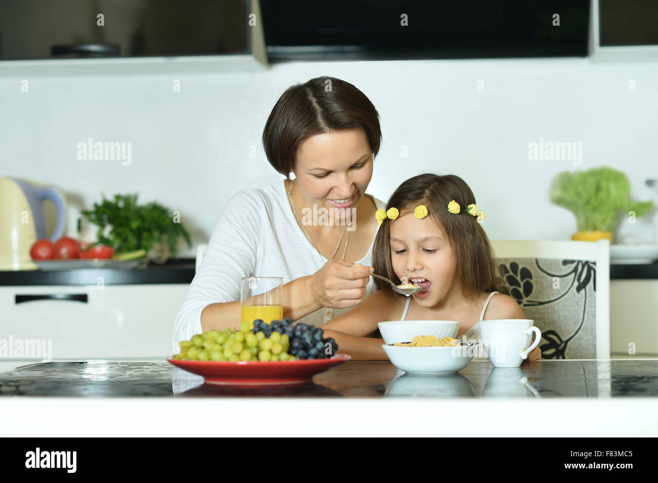 Little girl with mother eating Stock Photo - Alamy