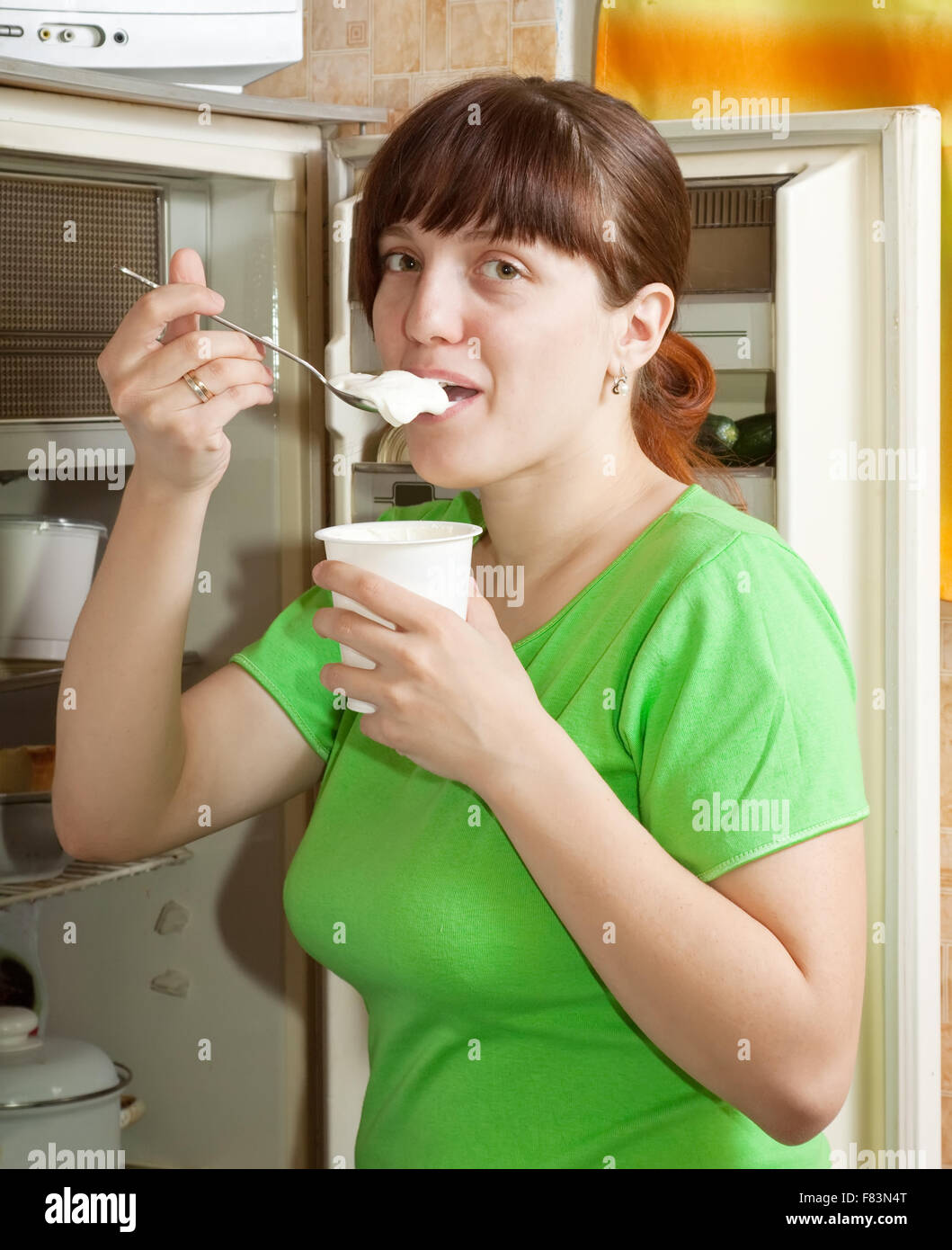Young woman eating dairy cream from fridge at home Stock Photo - Alamy