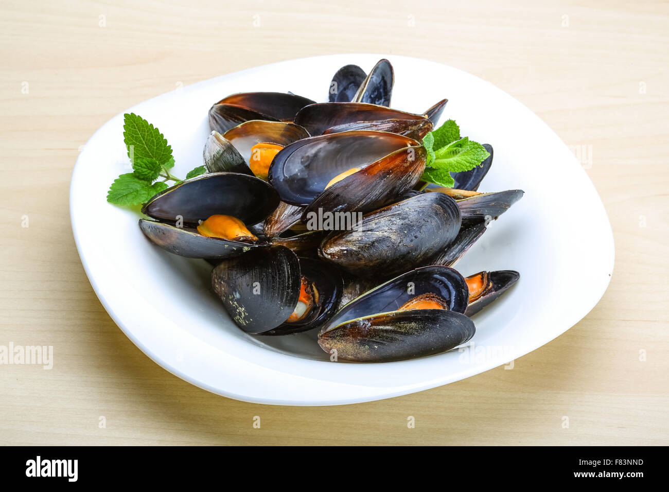 Fresh tasty Boiled mussels with herbs on wood background Stock Photo ...