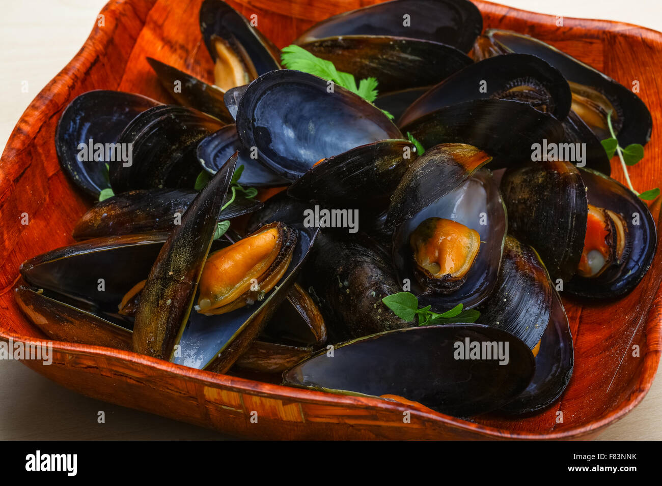 Fresh tasty Boiled mussels with herbs on wood background Stock Photo ...