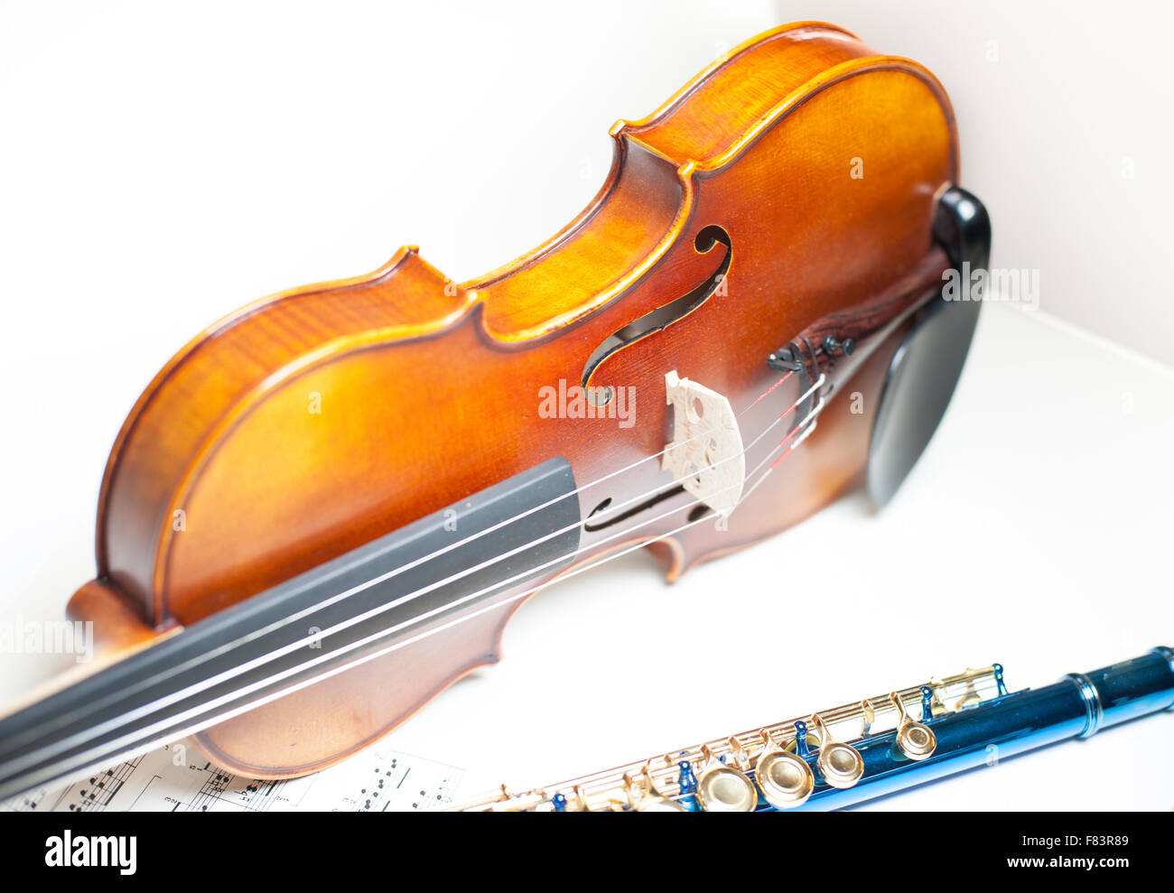 Wood violin body part detail with strings and f-hole, and blue flute ...
