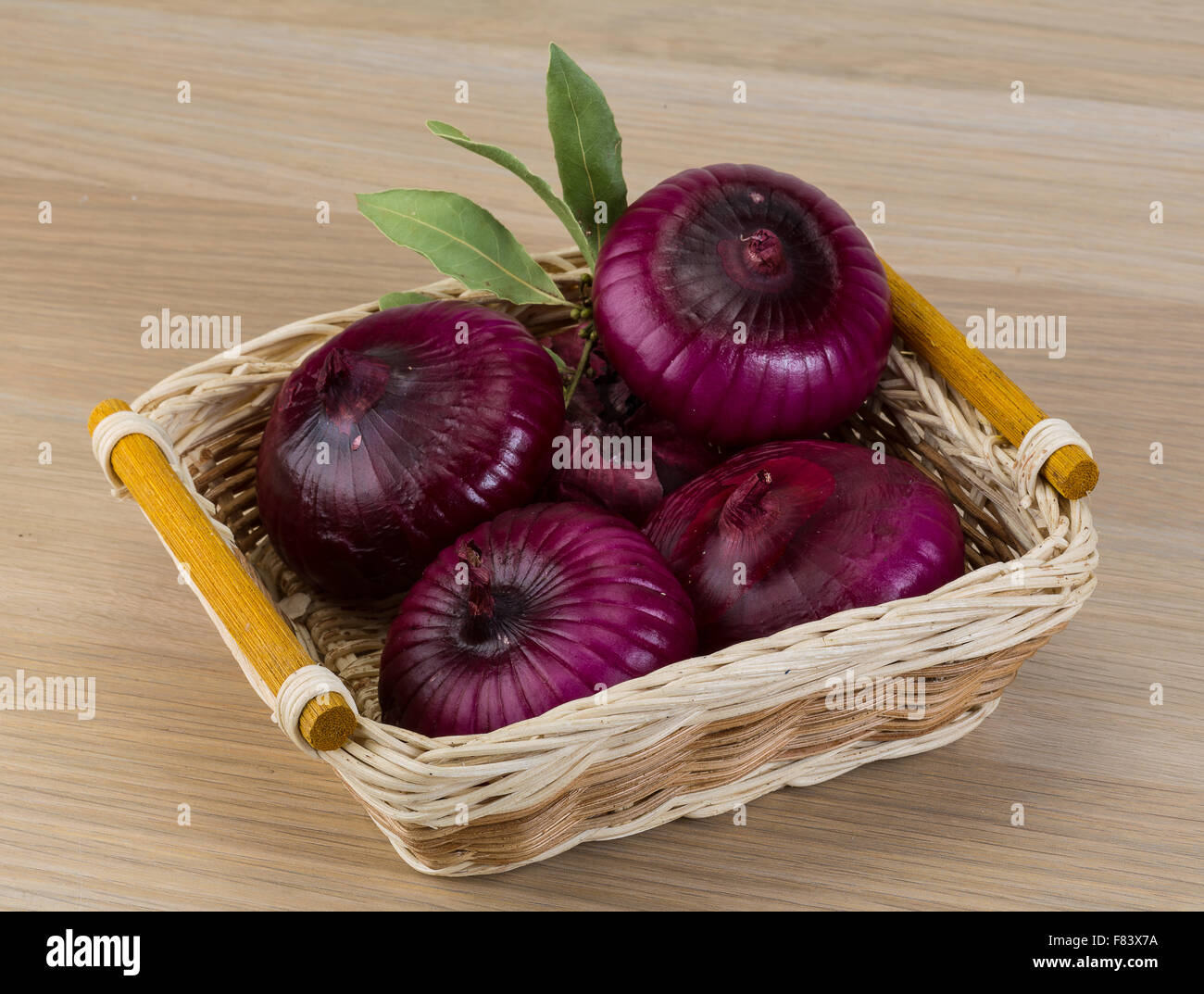 Violet onion in the basket with green Stock Photo - Alamy